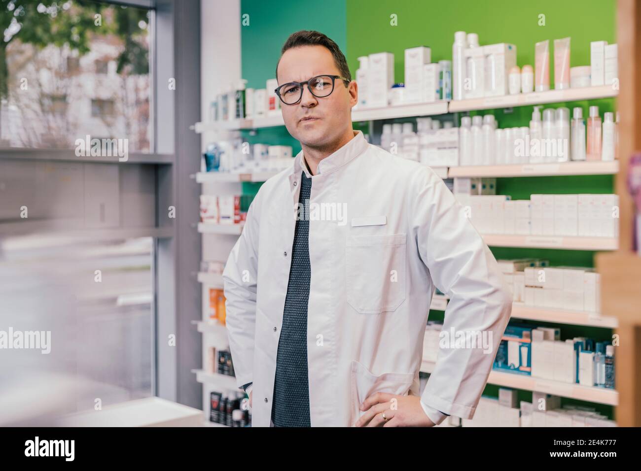 Contemplating pharmacist wearing lab coat while standing in chemist ...