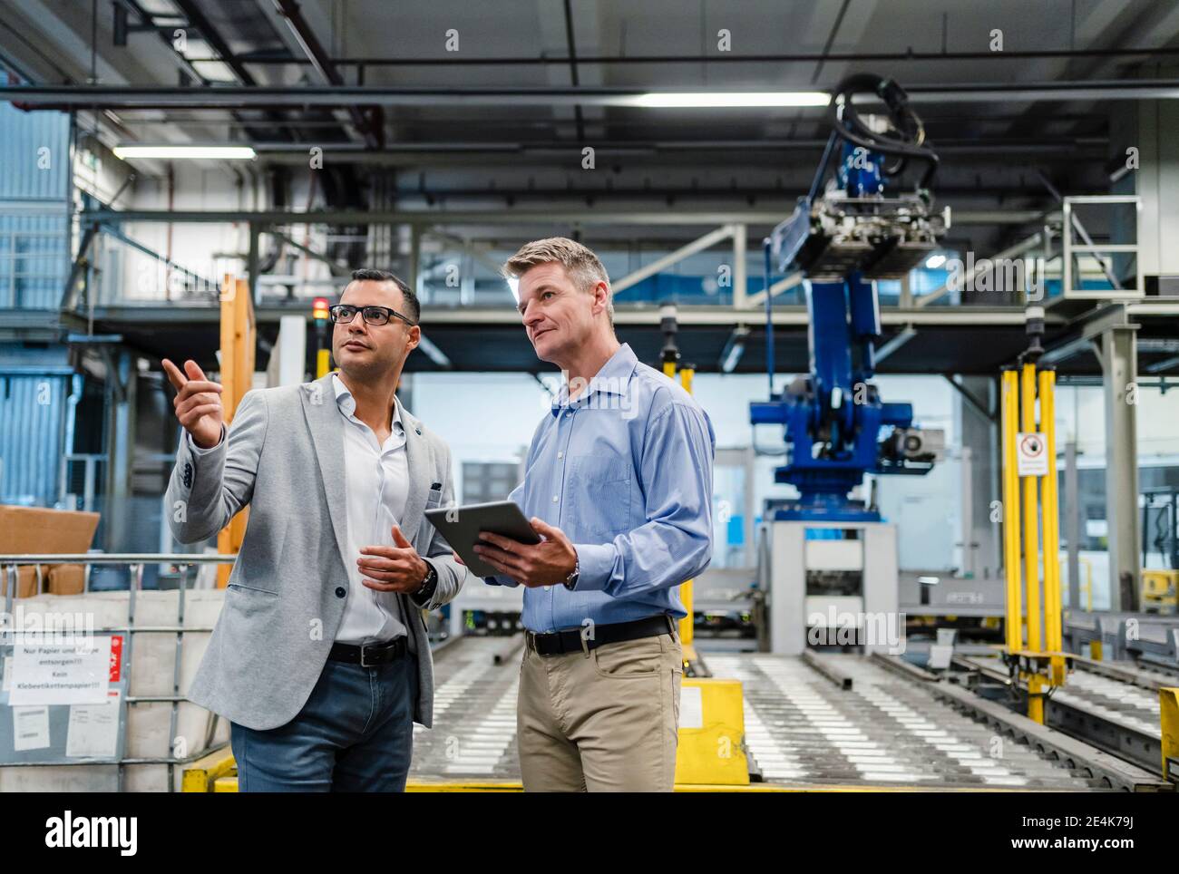 Male entrepreneur pointing while talking with supervisor in factory ...