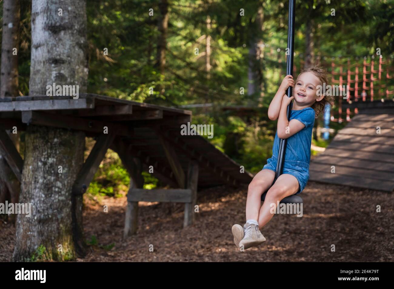 Little girl riding forest zip line Stock Photo - Alamy