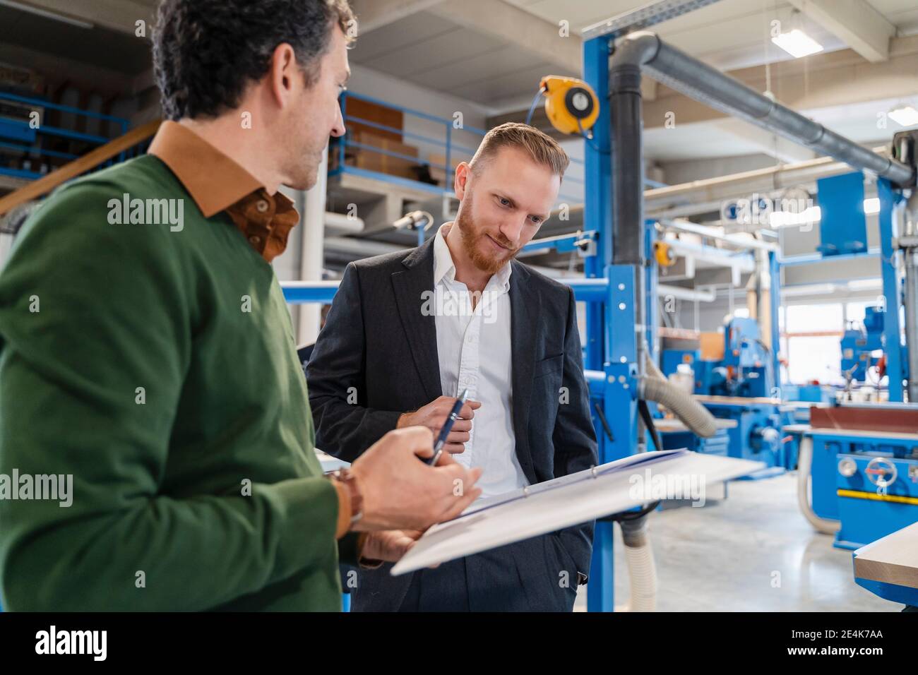 Two carpenters talking over documents in production hall Stock Photo ...