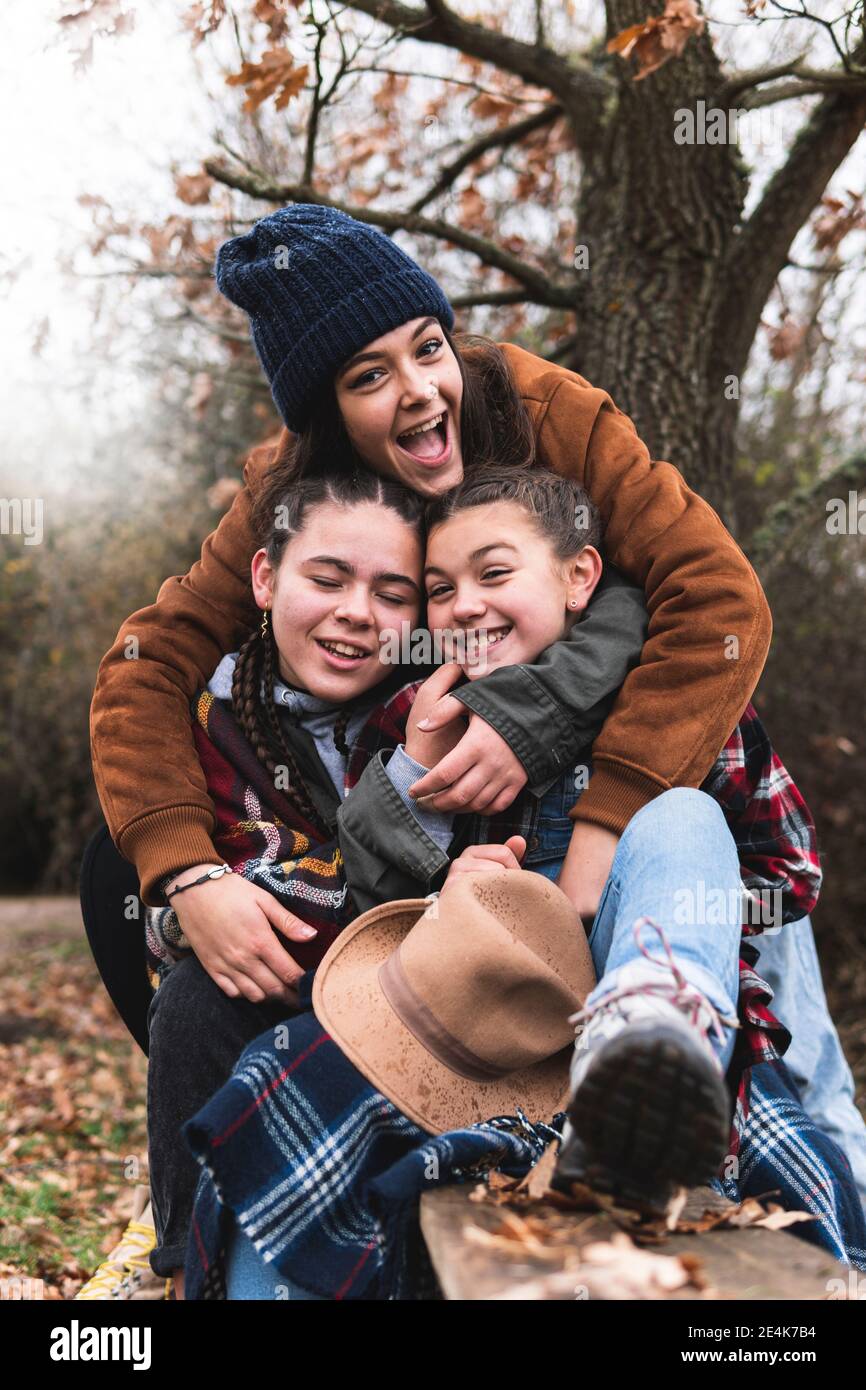 Three smiling sisters on bench in Autumn landscape Stock Photo - Alamy