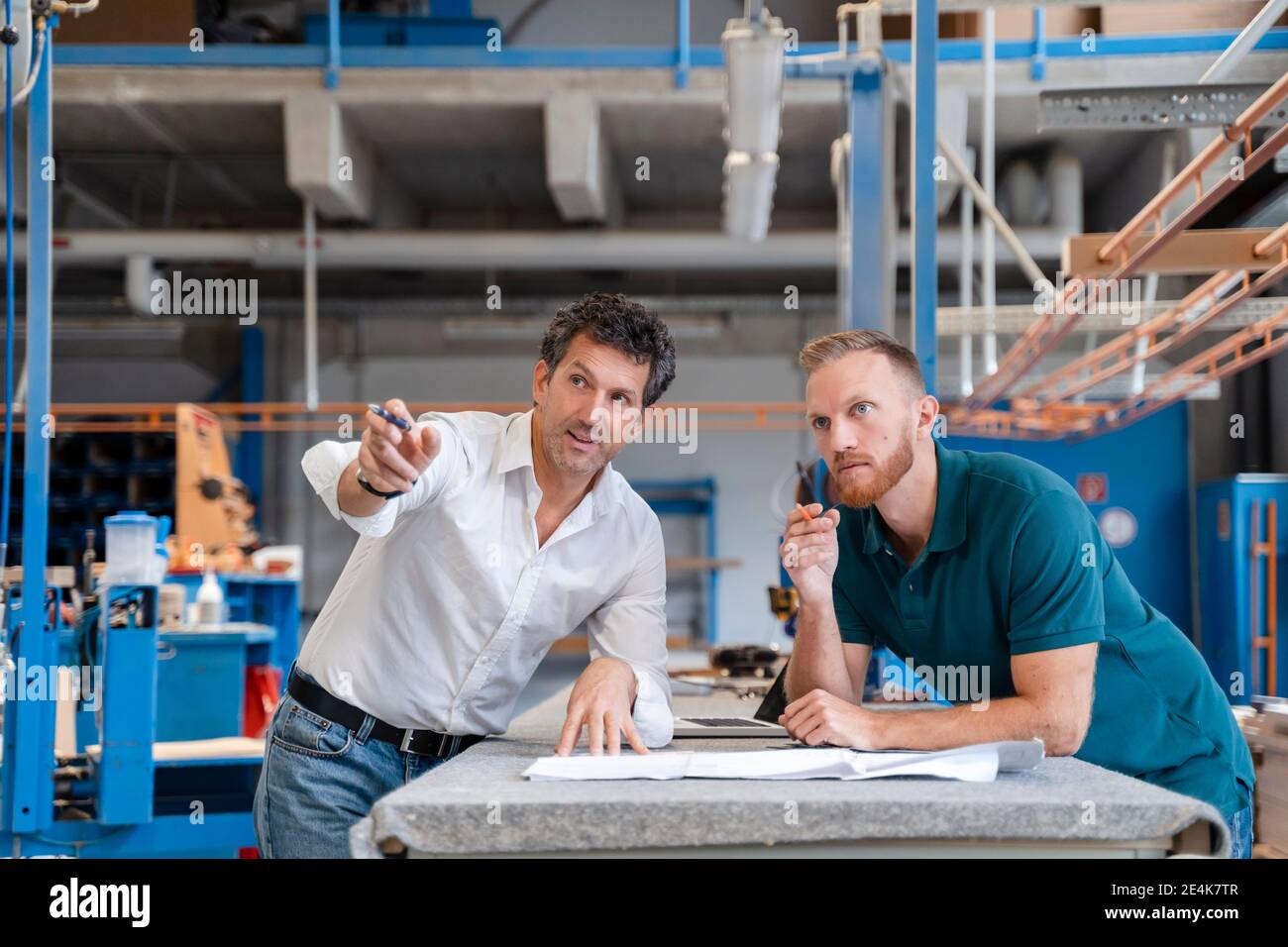 Two carpenters talking over documents in production hall Stock Photo ...