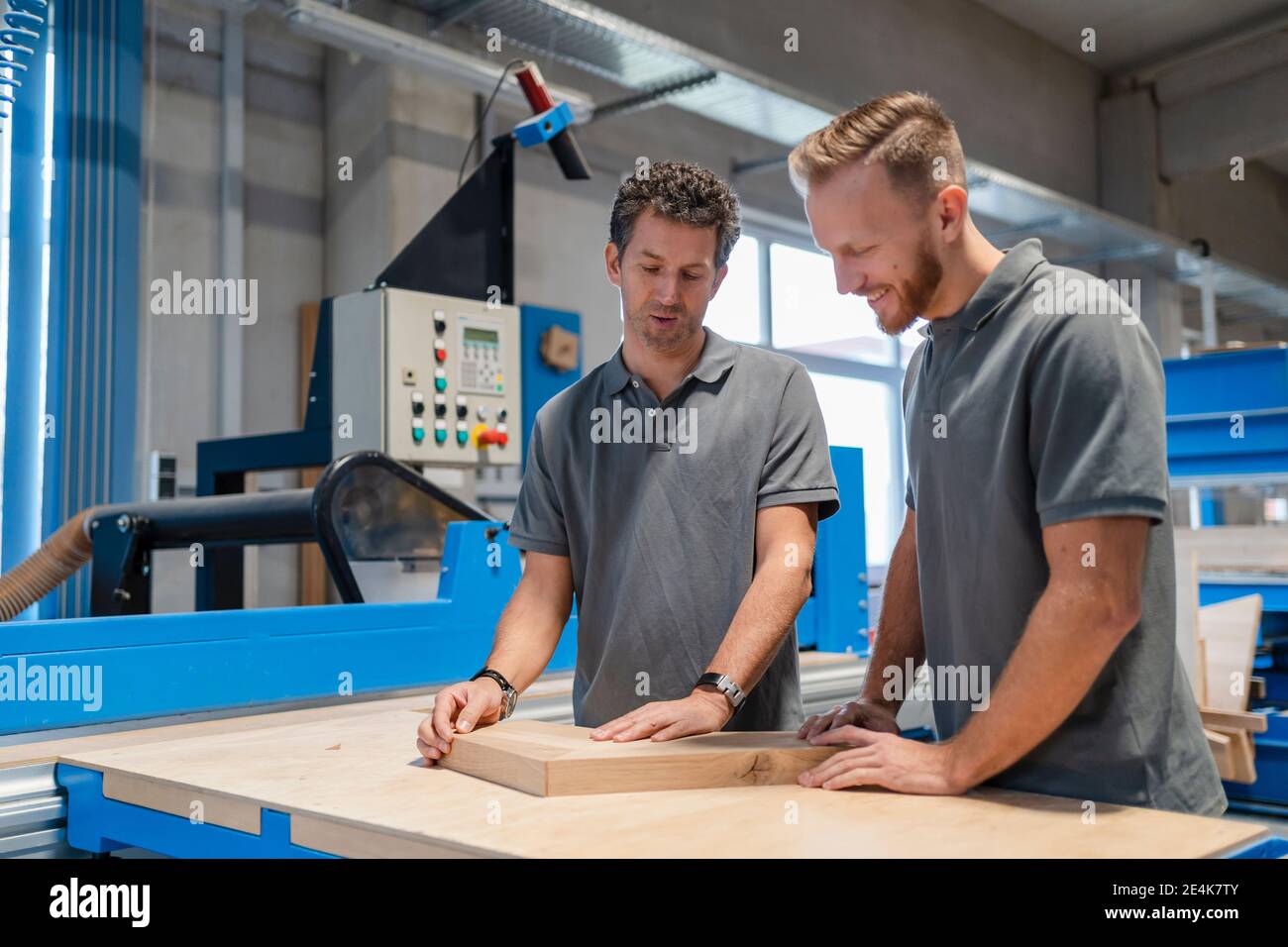 Two carpenters talking while examining wood in production hall Stock ...