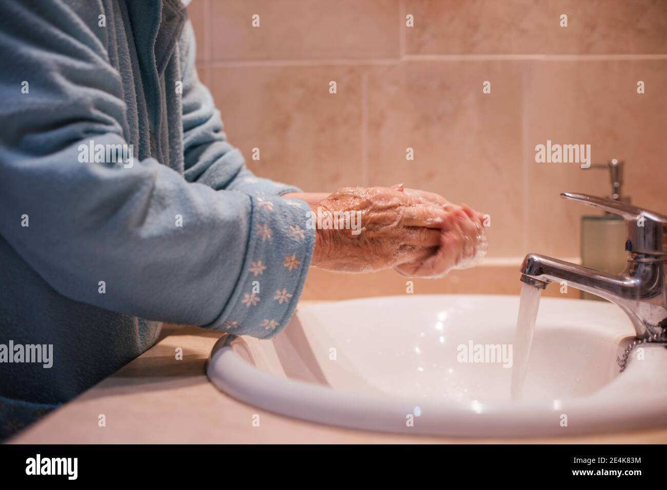 Senior woman washing hands by sink at home Stock Photo - Alamy