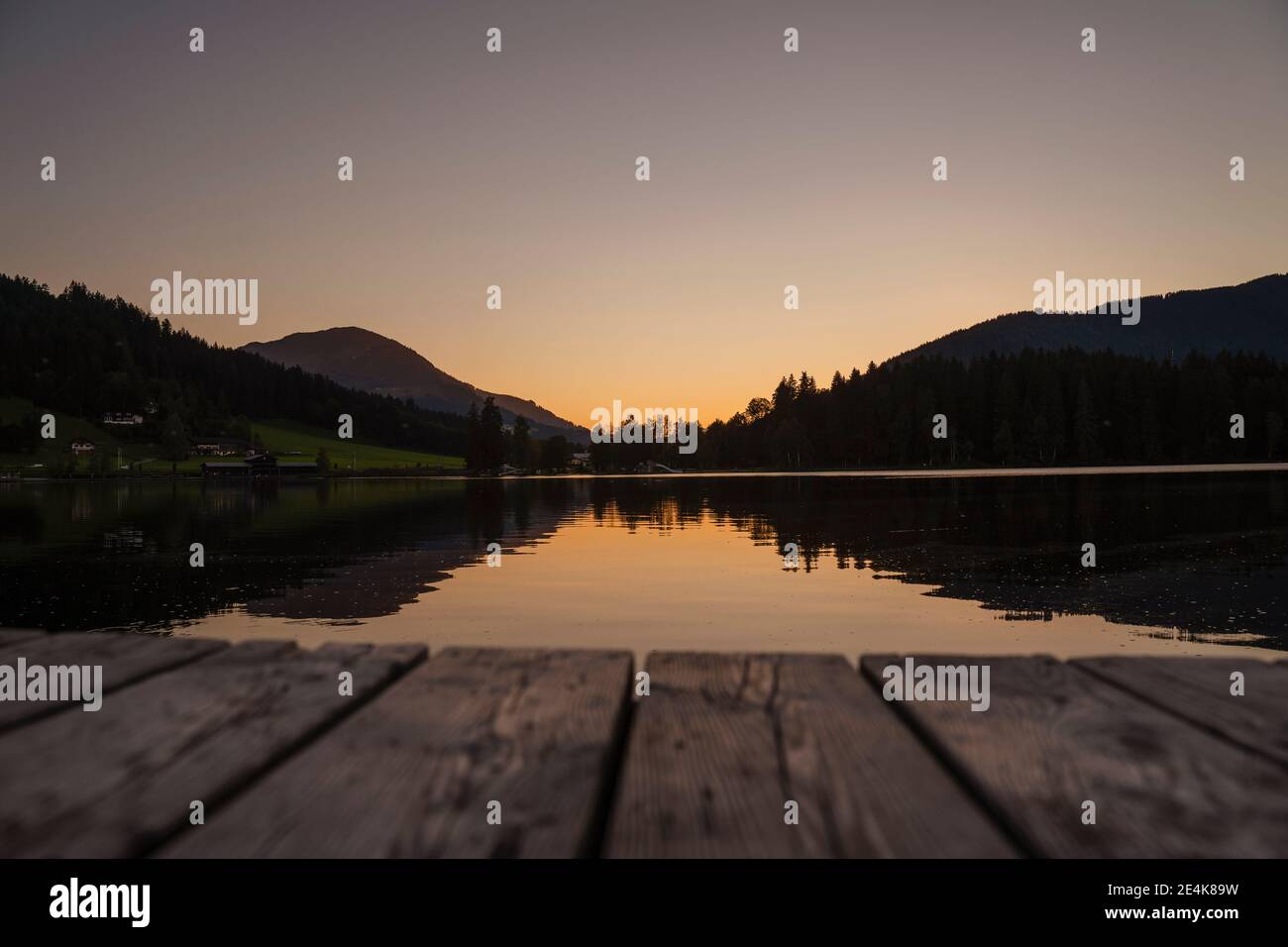 Mountains reflecting in shiny lake at dusk with edge of jetty in ...