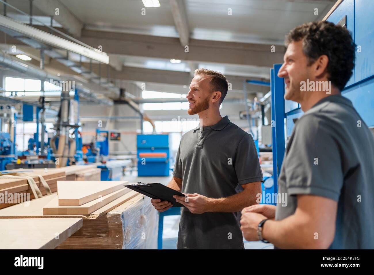 Two carpenters standing and talking in production hall Stock Photo - Alamy