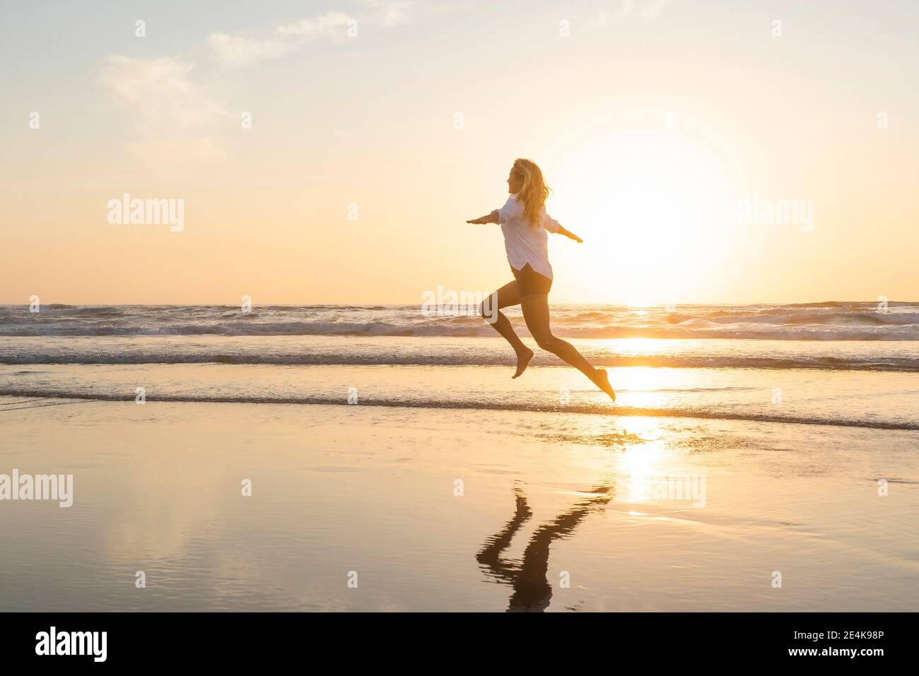 Happy woman with arms outstretched jumping against sea Stock Photo - Alamy