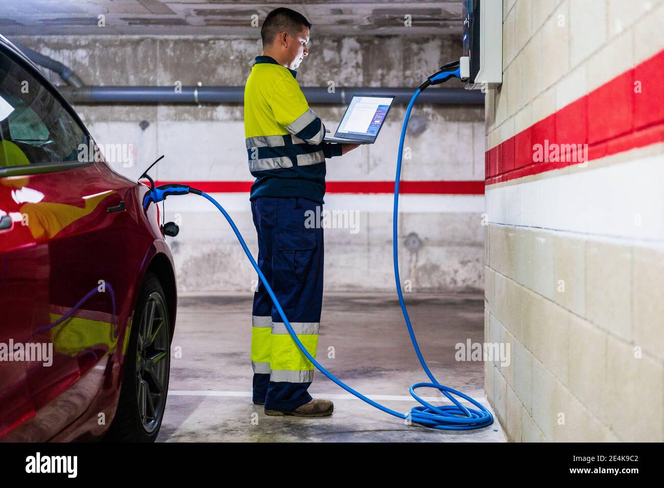 Professional male technician programming on laptop while charging ...