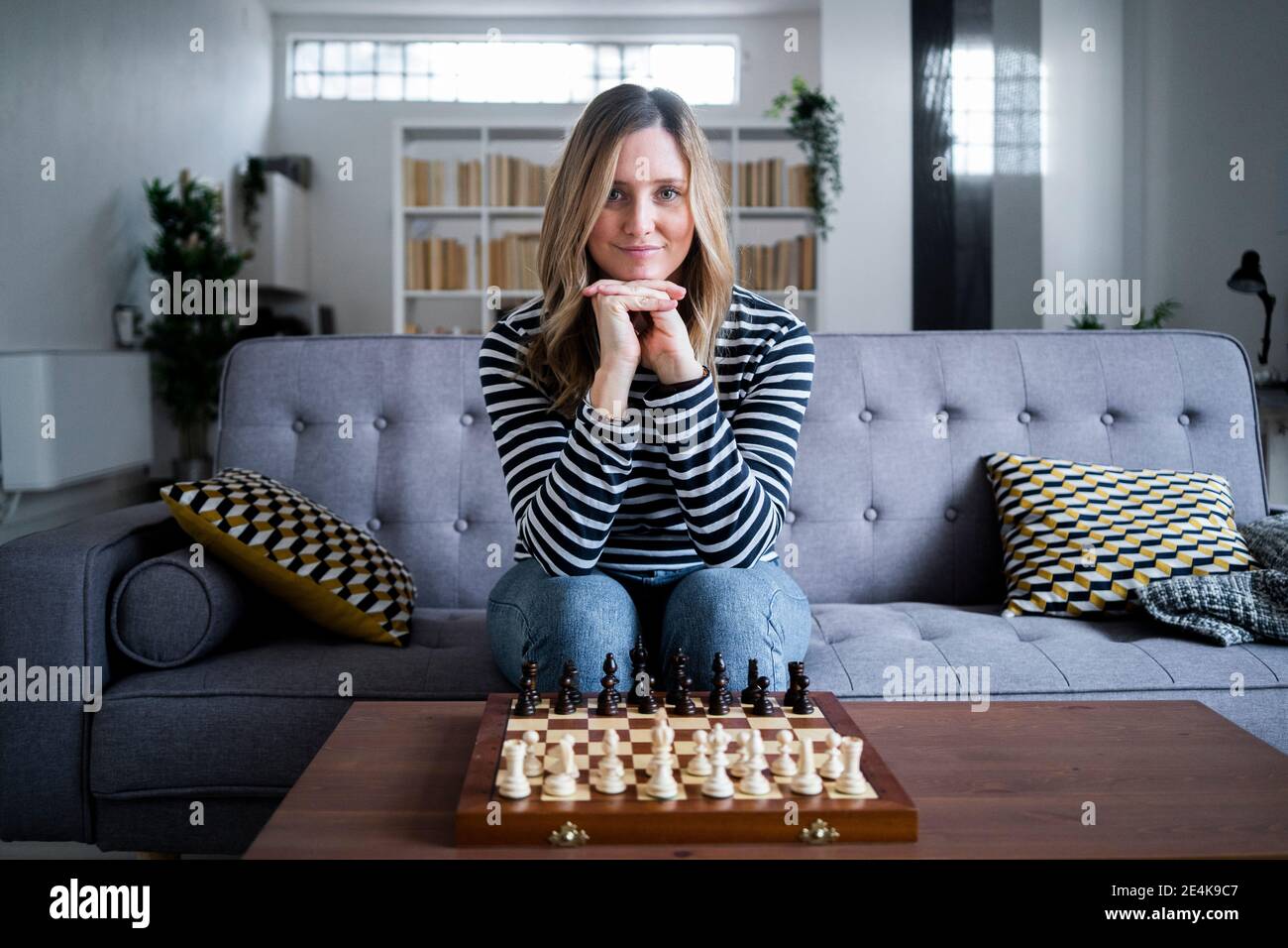 Portrait of woman sitting on sofa in front of chess board Stock Photo - Alamy