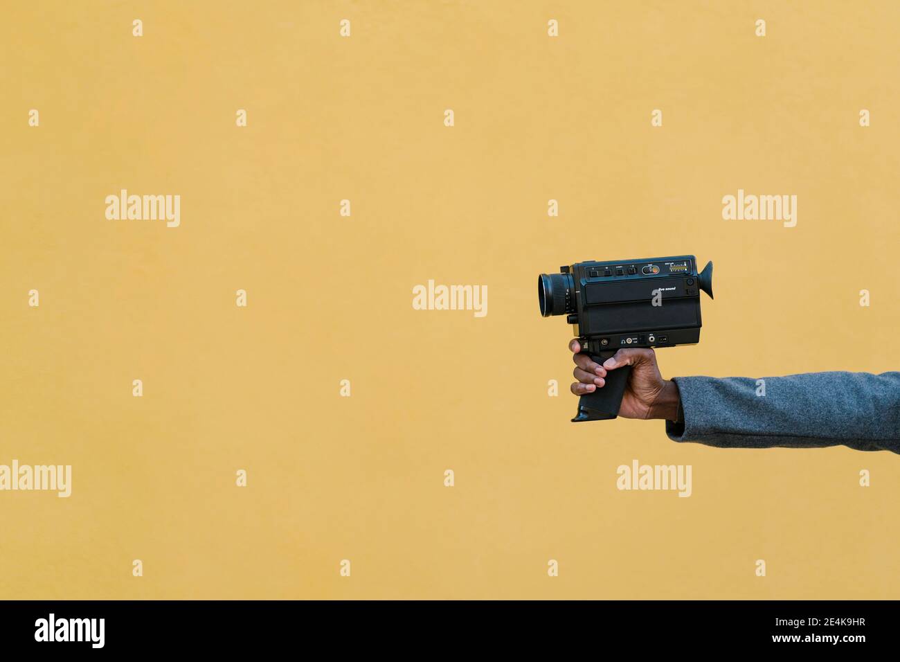 Man holding 1980s camera against yellow wall Stock Photo - Alamy