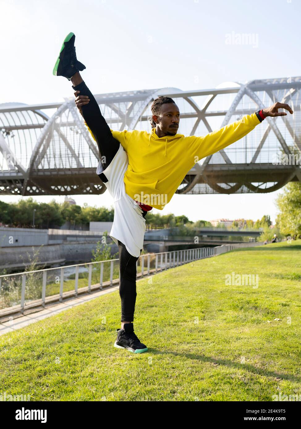 Sportsman doing splits yoga while standing against walkway Stock Photo ...