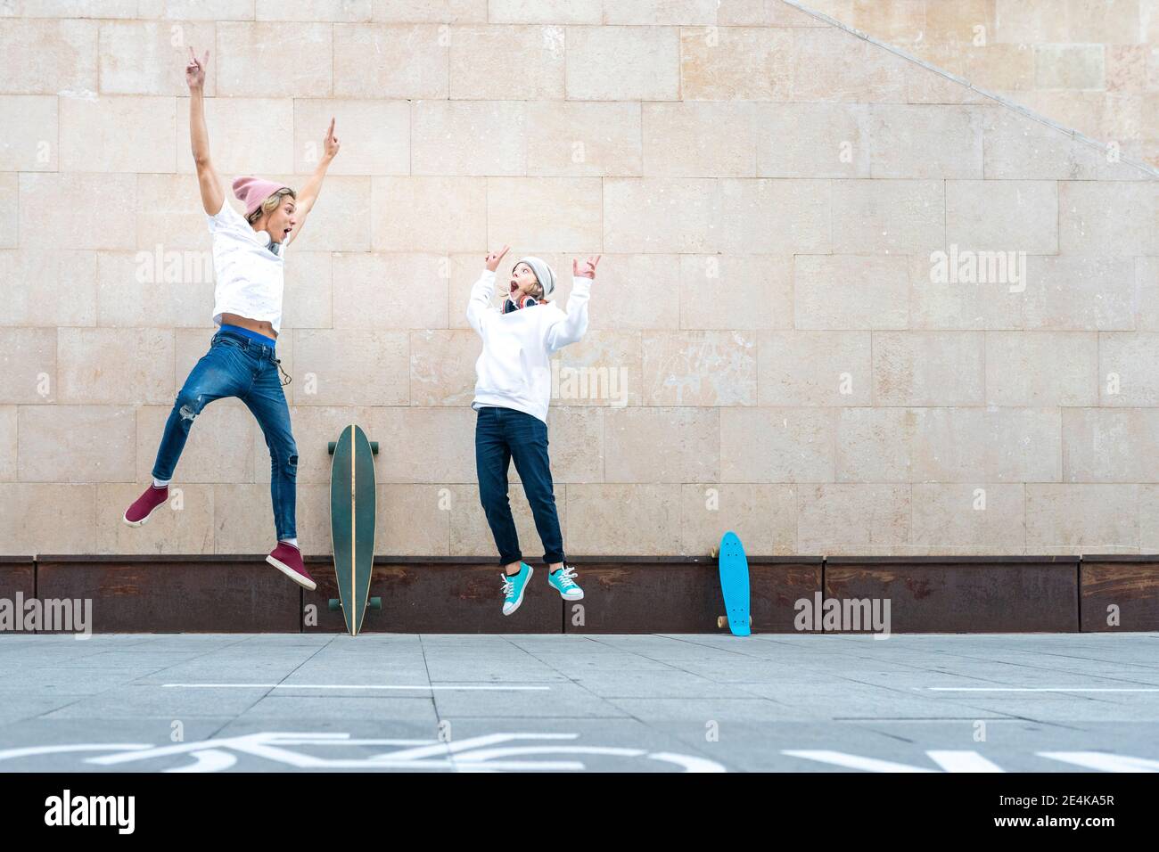 Happy friends dancing while jumping against wall Stock Photo - Alamy