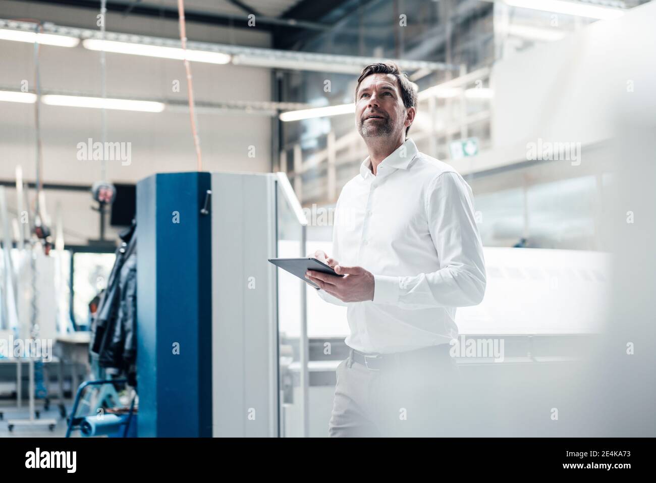 Male inspector with digital tablet examining equipment while standing ...