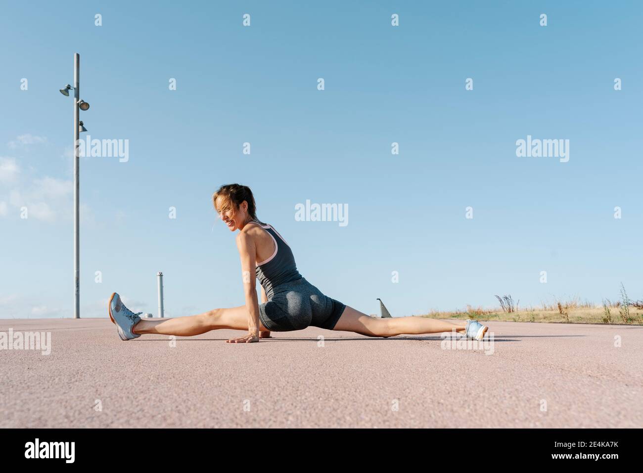 Female sportsperson exercising splits on sunny day Stock Photo - Alamy