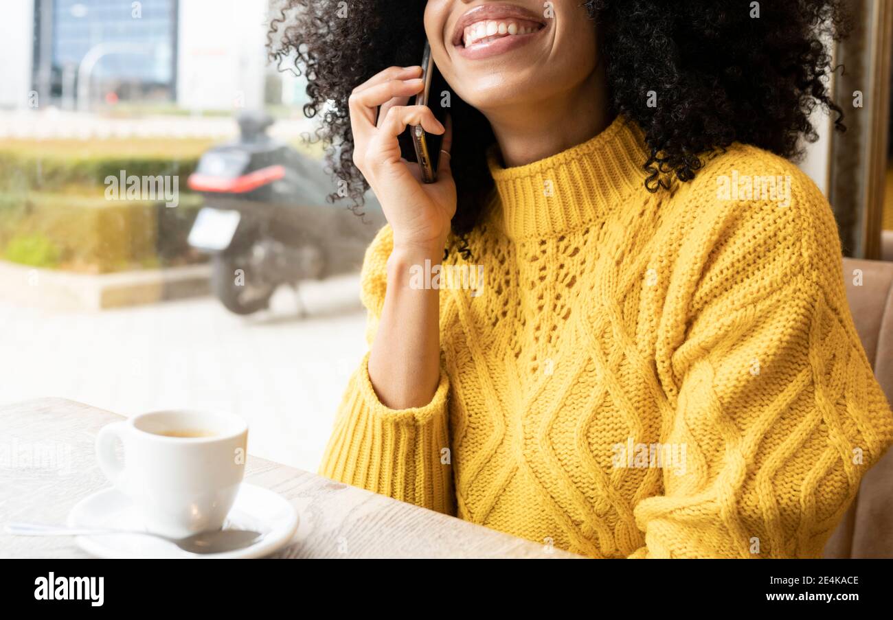 Woman smiling while talking on mobile phone sitting at cafe Stock Photo ...