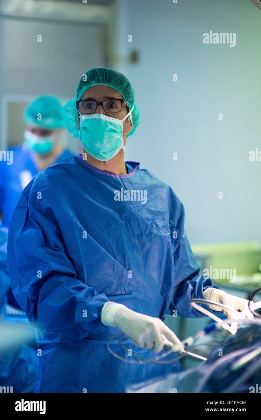 Male surgeon wearing glove using tweezers and thread in operating room ...