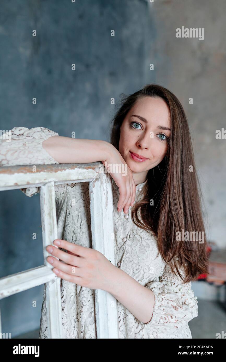 Beautiful woman with old window frame standing against wall Stock Photo ...