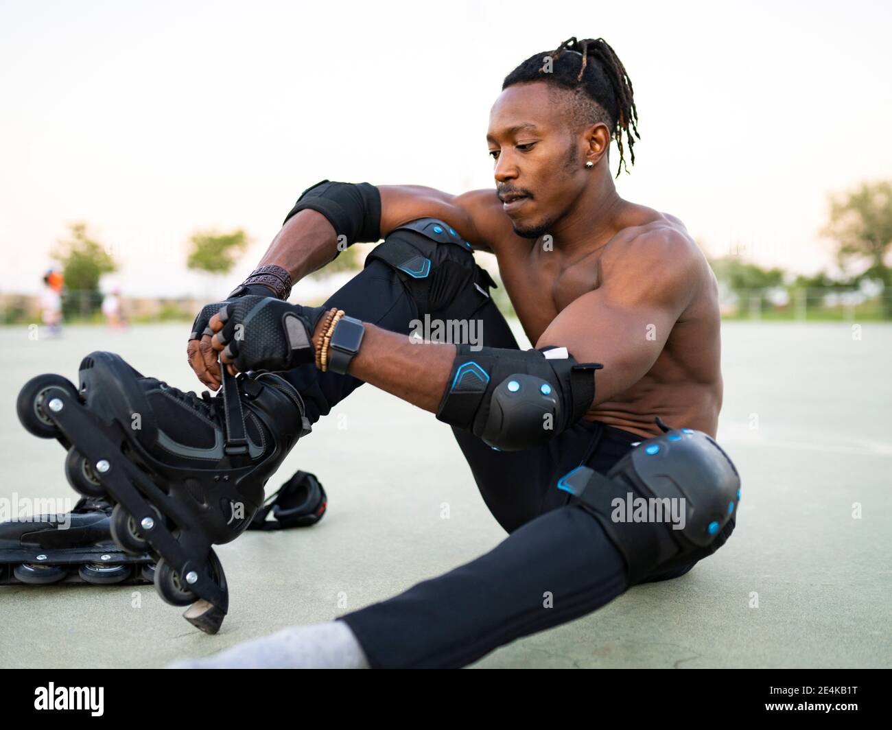 Athlete wearing roller skate while sitting on ground Stock Photo - Alamy
