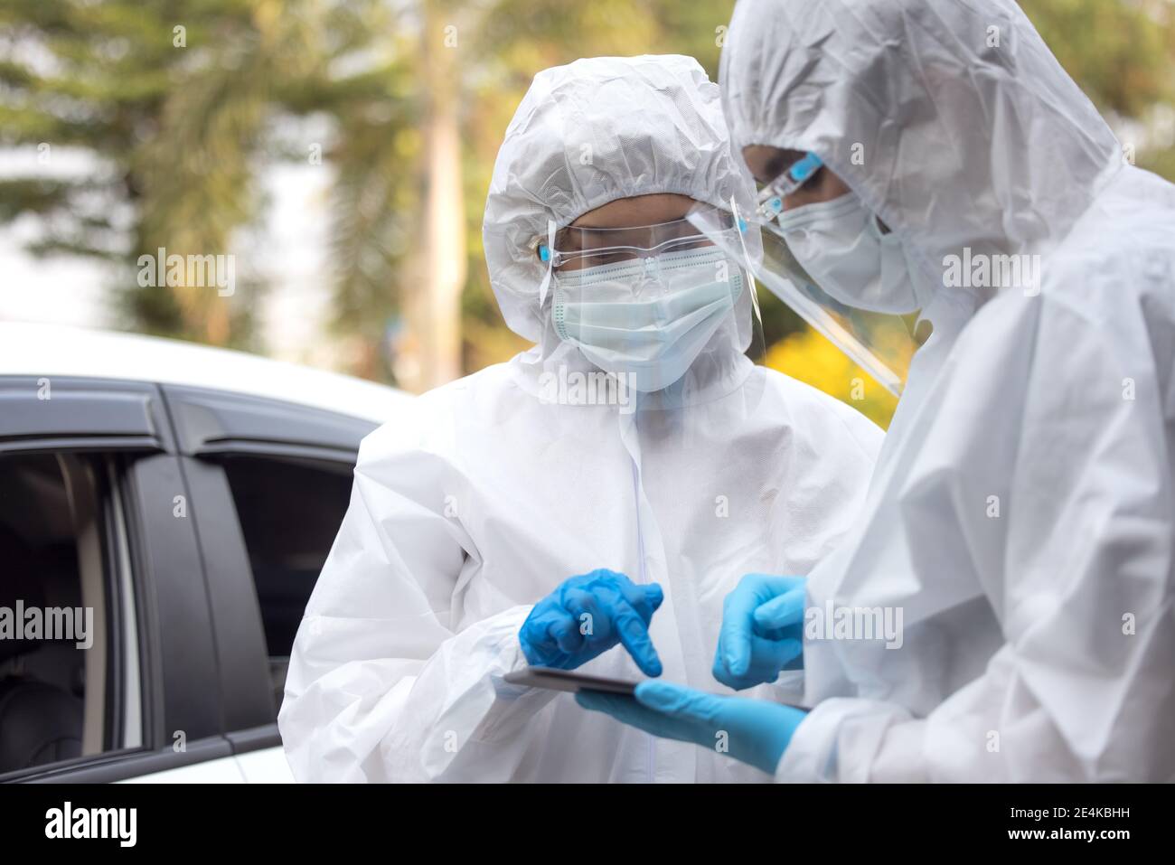 Doctors in ppe suit using tablet with face shield discussing standing ...