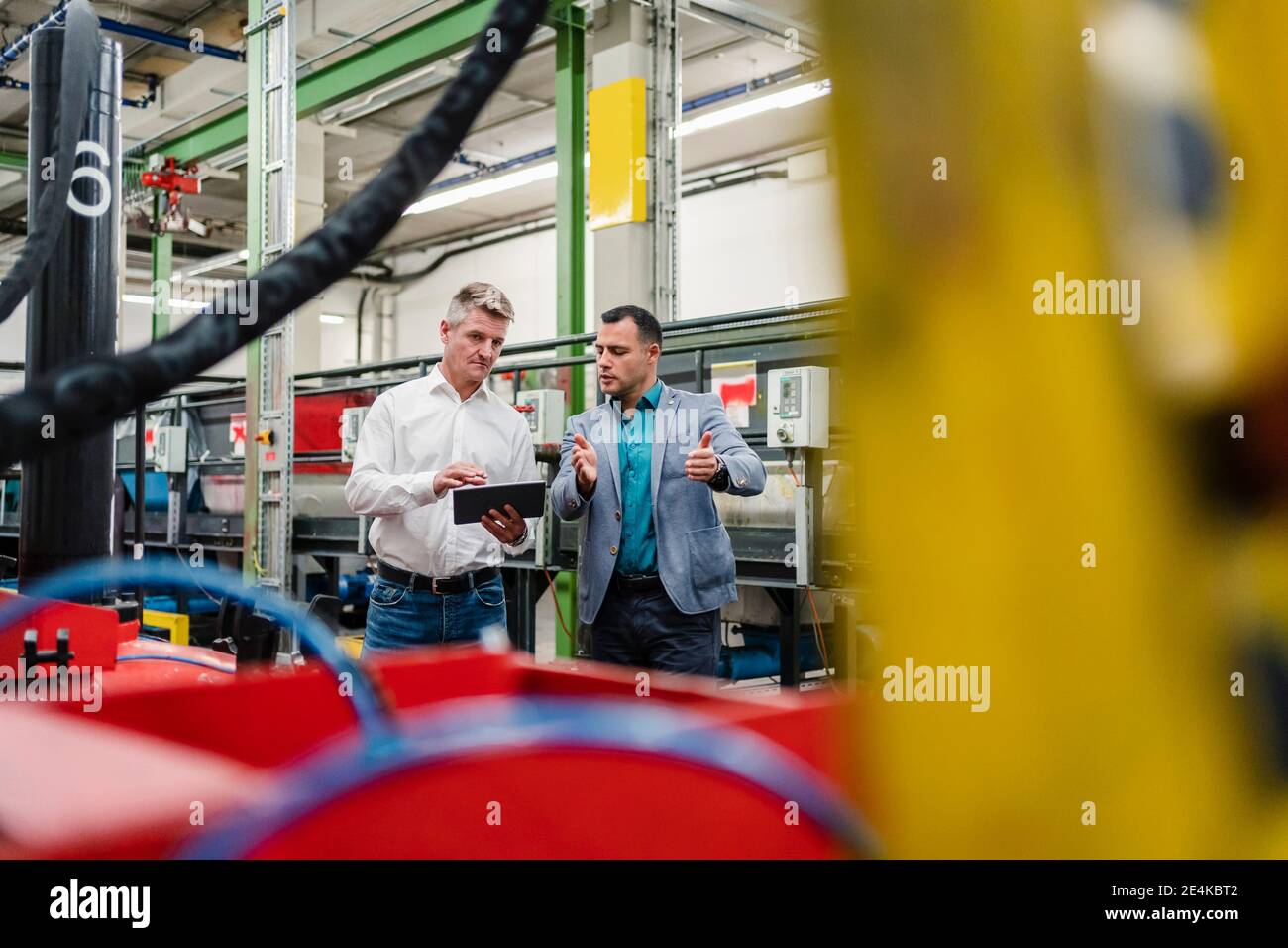 Male engineer and supervisor working on digital tablet together in ...