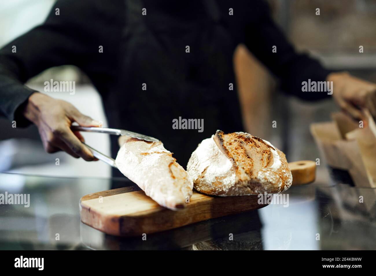 Salesman packing fresh bread while working at bakery Stock Photo - Alamy