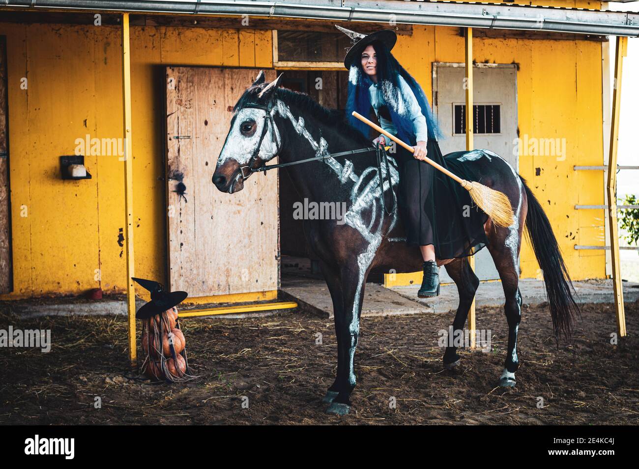 A girl dressed as a witch with a broom sits on a horse on which a ...