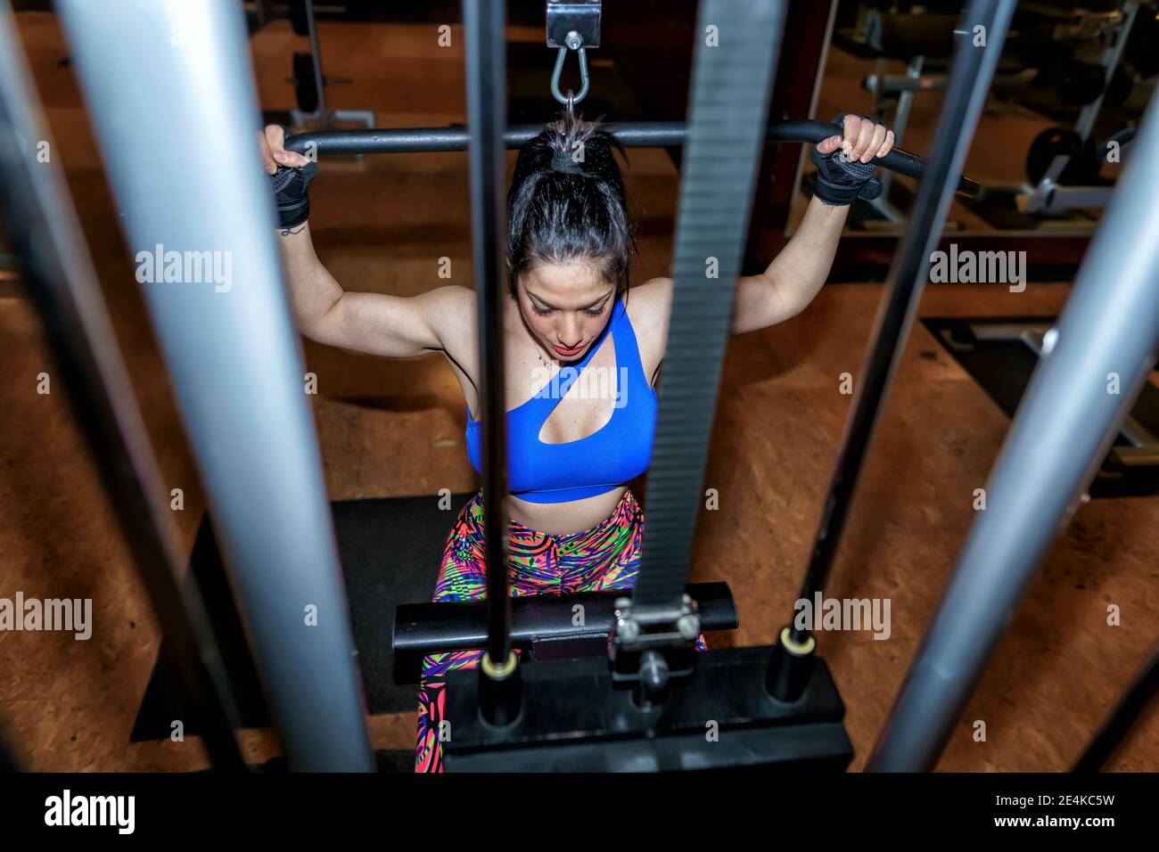 Mid adult woman pulling exercise machine in health club Stock Photo - Alamy
