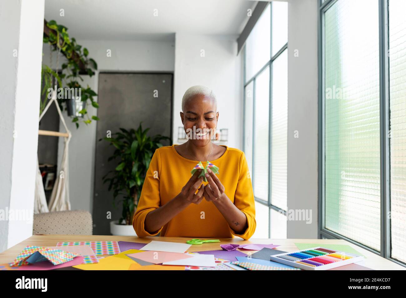 Origami artist sitting in studio working with colorful paper Stock ...