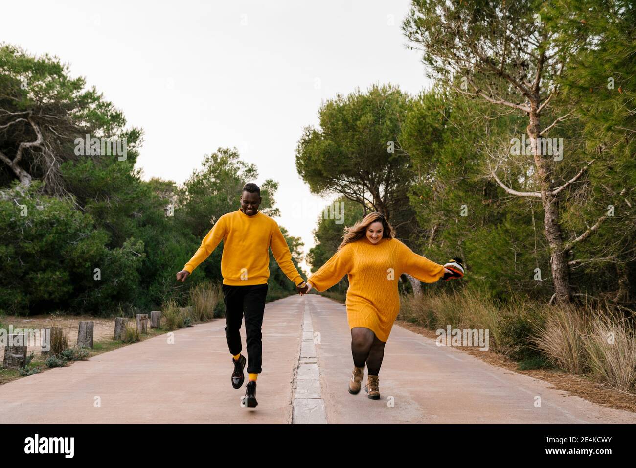 Carefree couple holding hands while running on road Stock Photo - Alamy