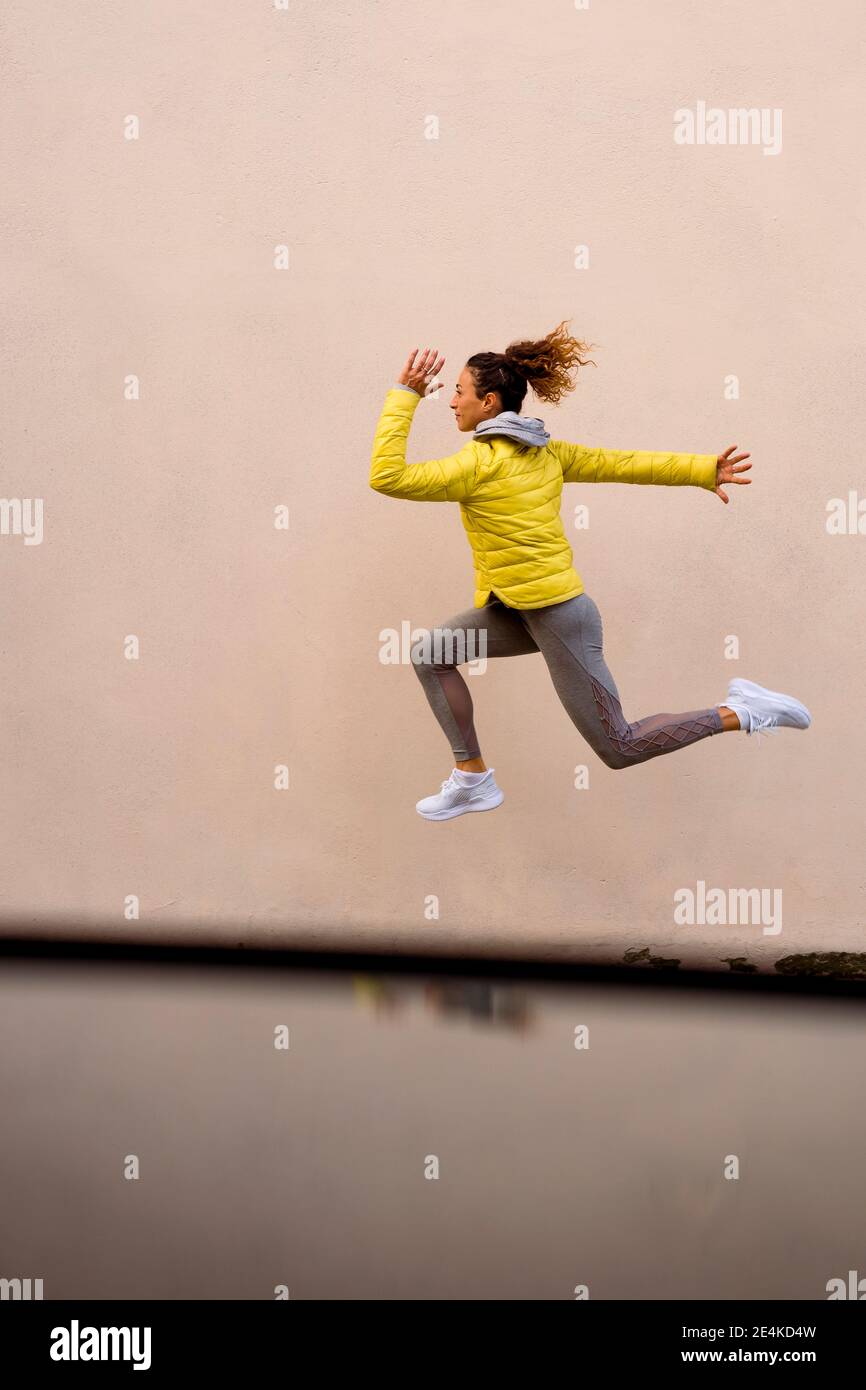 Female athlete running against pink wall Stock Photo - Alamy
