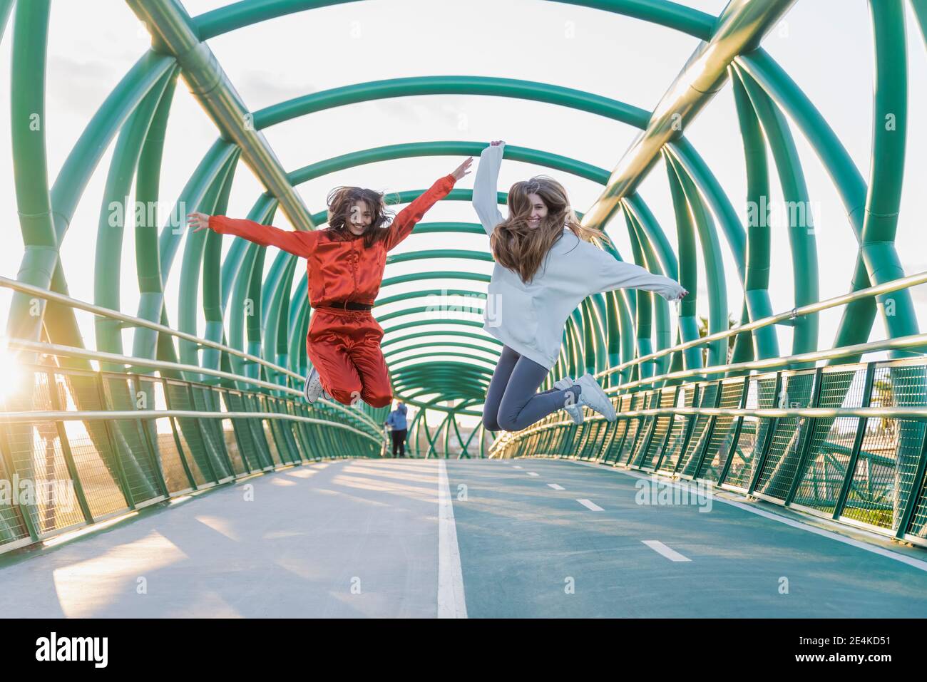 Carefree friends with arms outstretched jumping on bridge Stock Photo ...