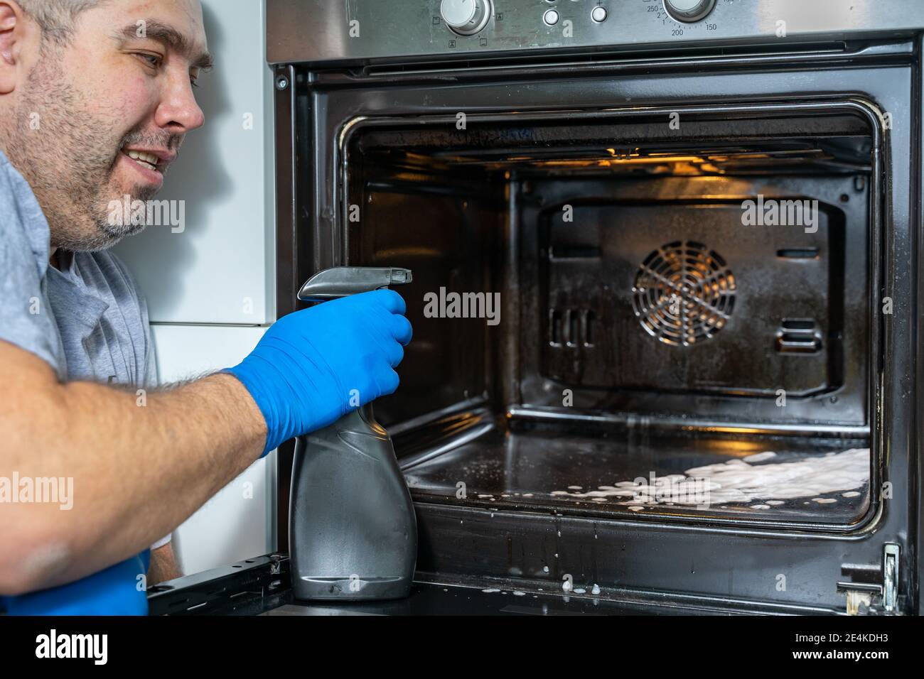 a man cleans the oven in his kitchen with a cleaning agent Stock Photo ...