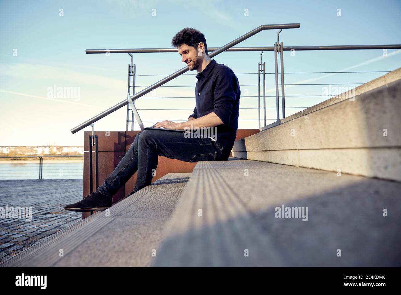 Entrepreneur using laptop while sitting on steps Stock Photo - Alamy
