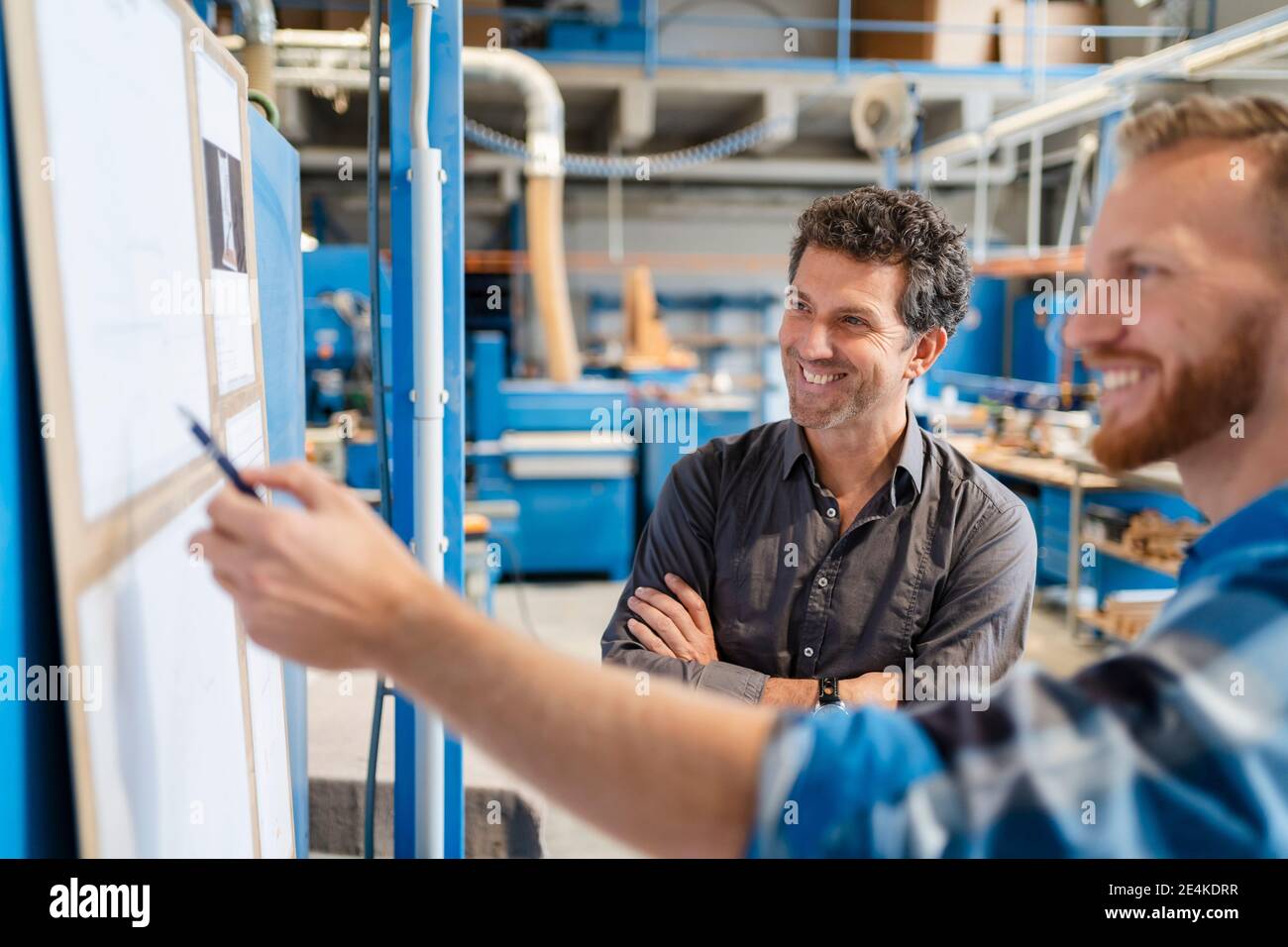 Two carpenters talking over documents in production hall Stock Photo ...