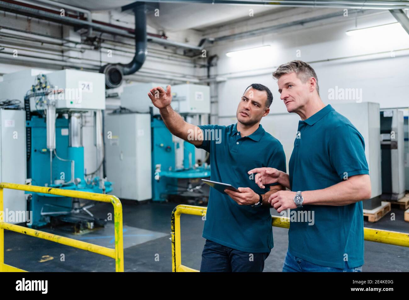 Male professionals talking about manufacturing while standing in ...