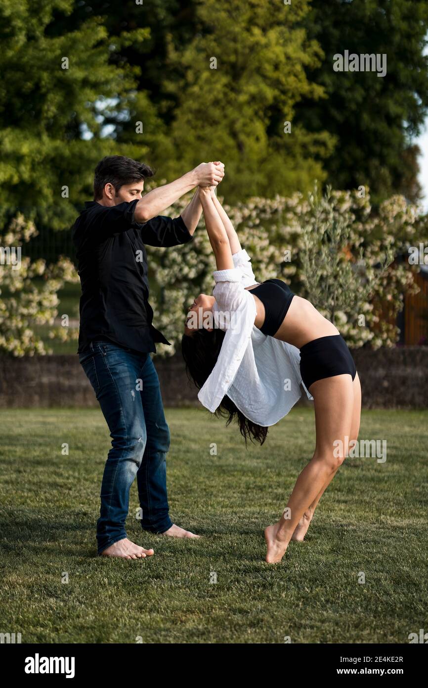 Male dancer holding hands of female dancer while standing on tiptoes ...