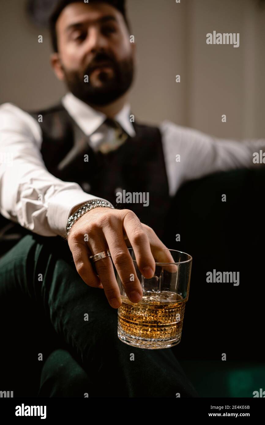 Arm of man holding glass of whiskey Stock Photo - Alamy