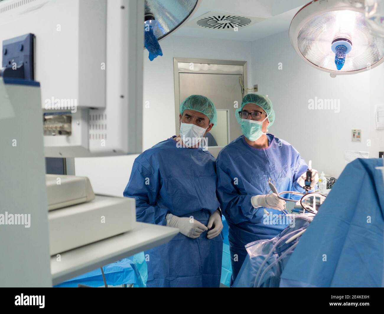 Male surgeon looking at monitoring equipment while doing surgery at ...