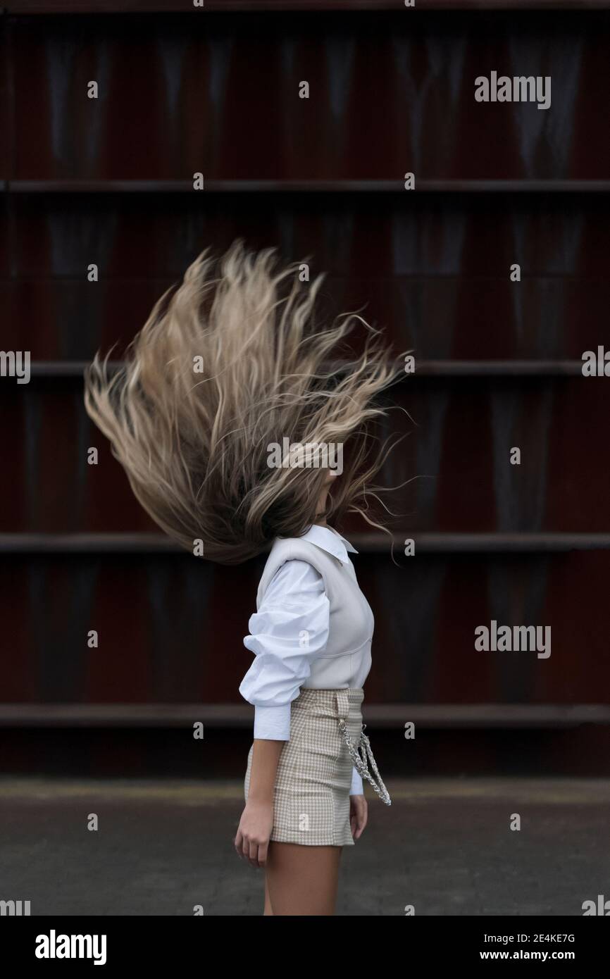 Fashionable woman with eyes closed tossing hair in front of wall Stock ...