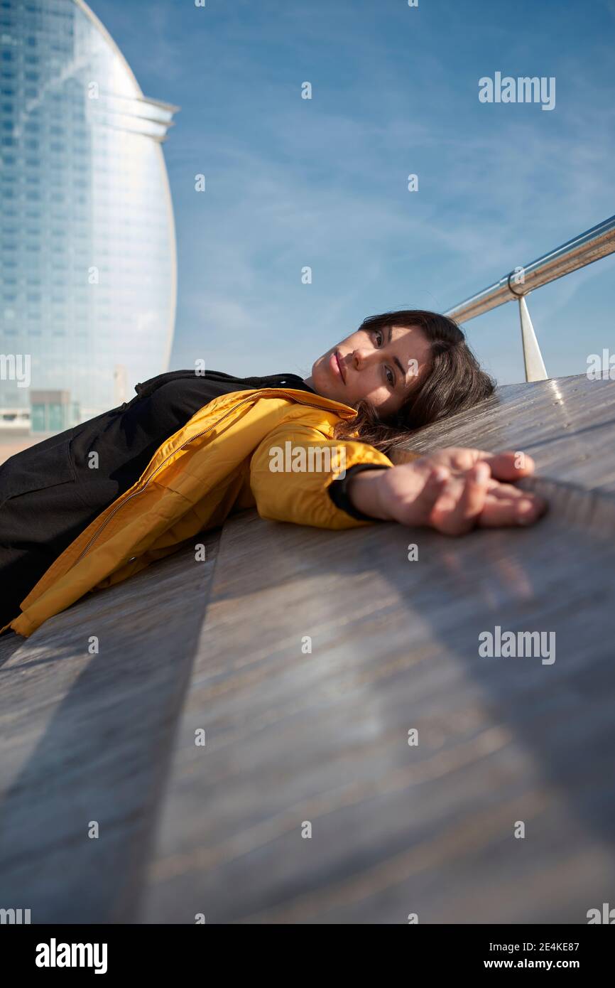 Beautiful woman lying on retaining wall during sunny day Stock Photo ...