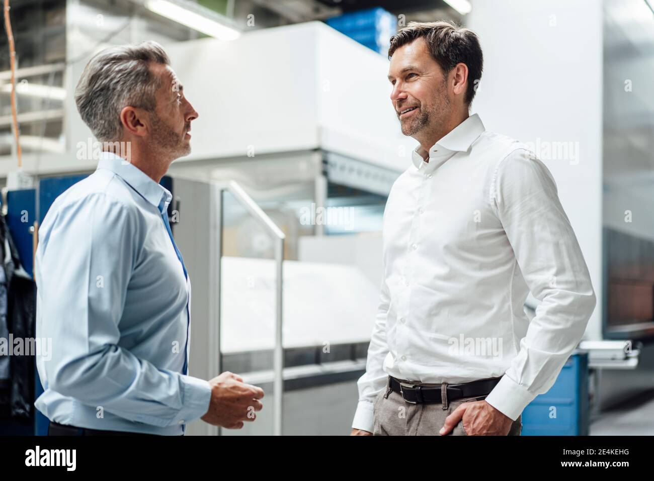 Business people having discussion while standing at industry Stock ...