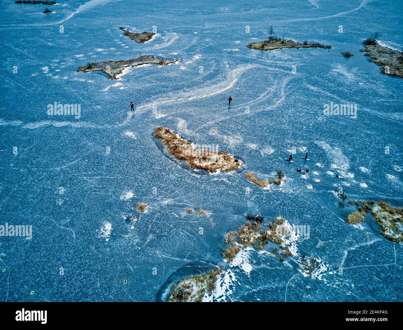 Aerial view of two fishermen walking on surface of frozen lake Stock ...