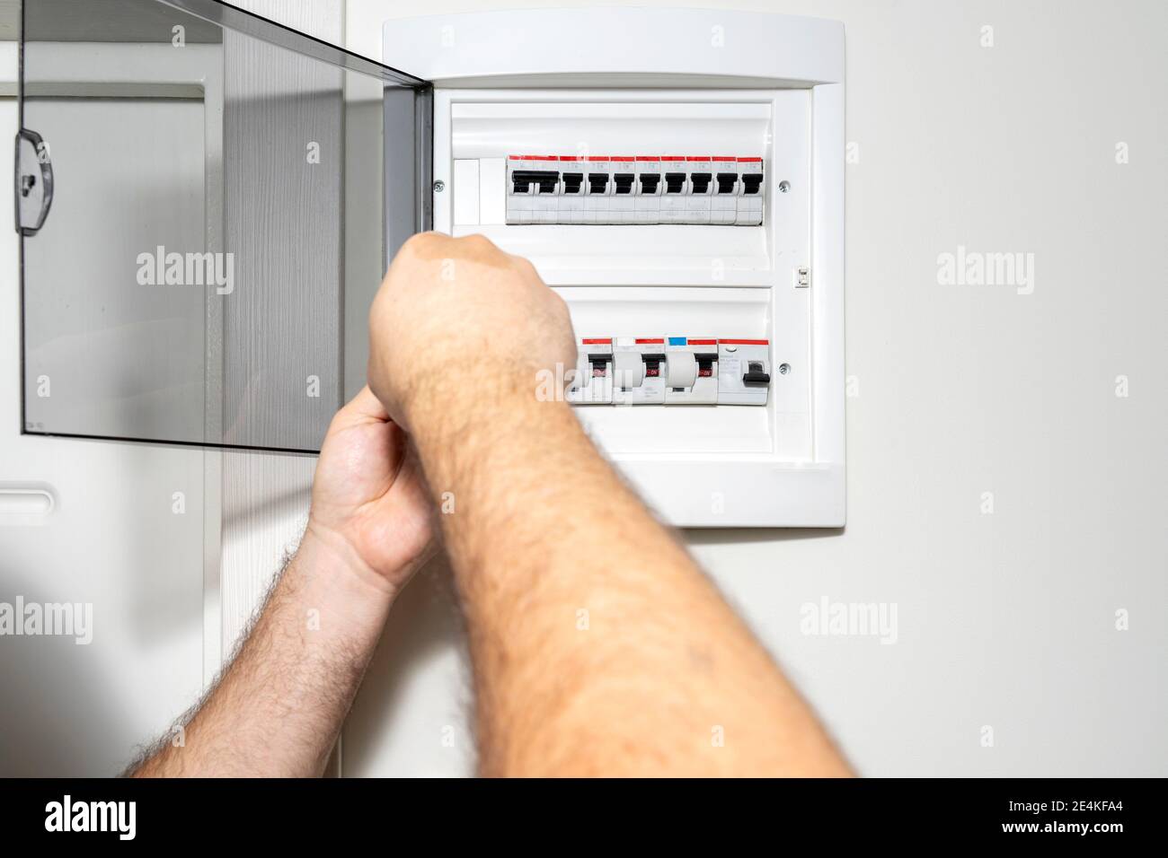 Electrician installing panel with electric meter in apartment of ...