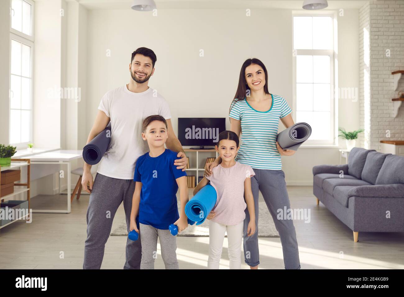 Happy family with kids holding sports equipment and smiling at camera ...