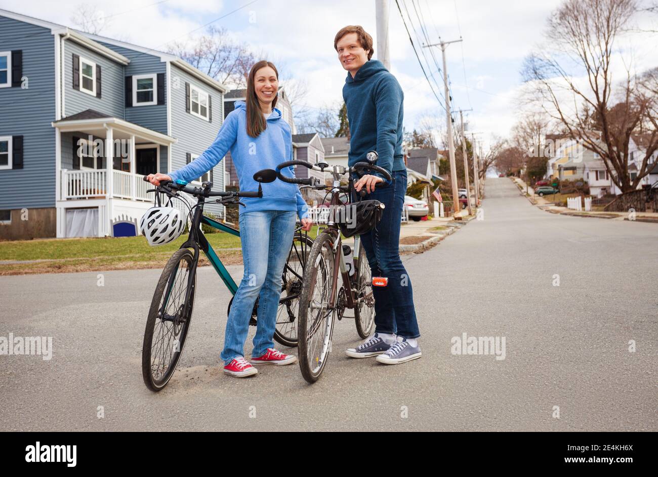 Happy young smiling couple stand with bicycles on urban street in a ...
