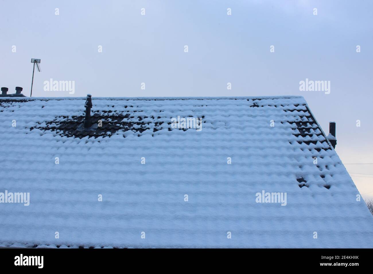 A photograph of a roof with aerial and chimneys, covered in a thin ...