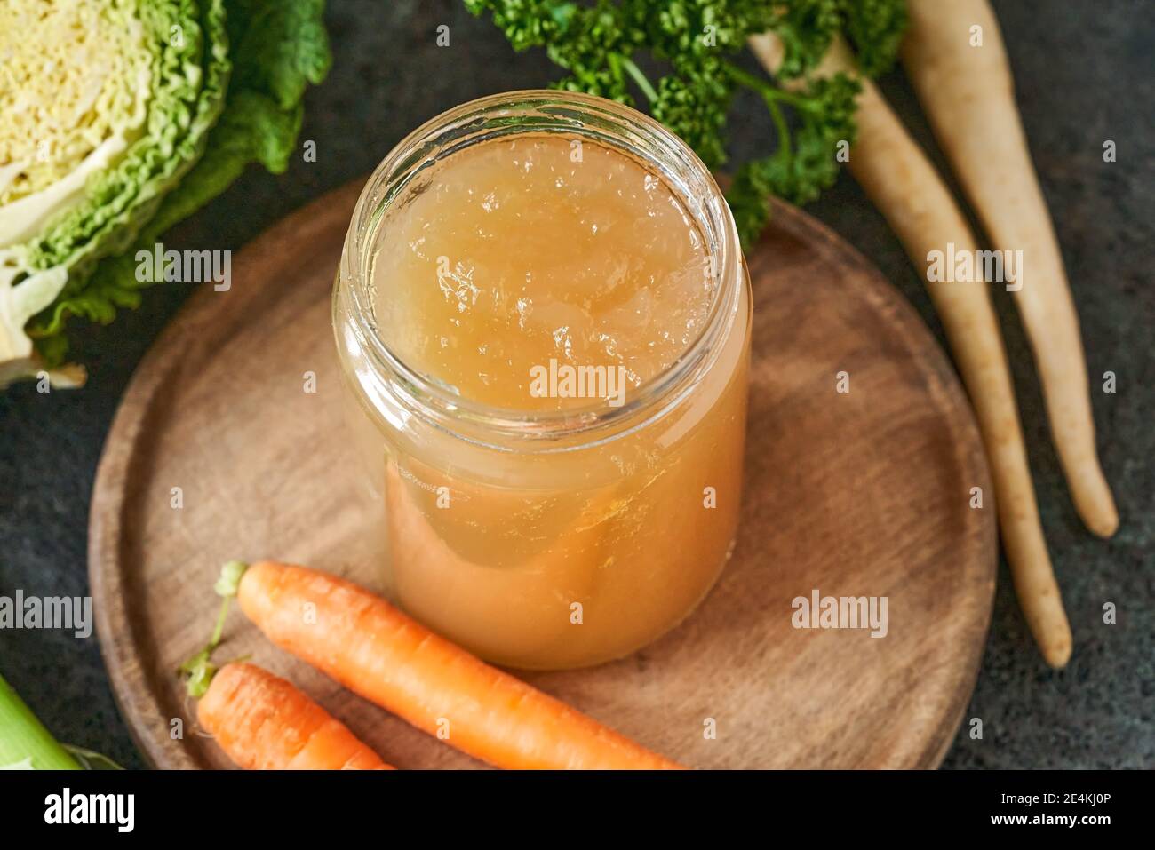 Cooled down congealed beef bone broth in a glass jar, with vegetables ...