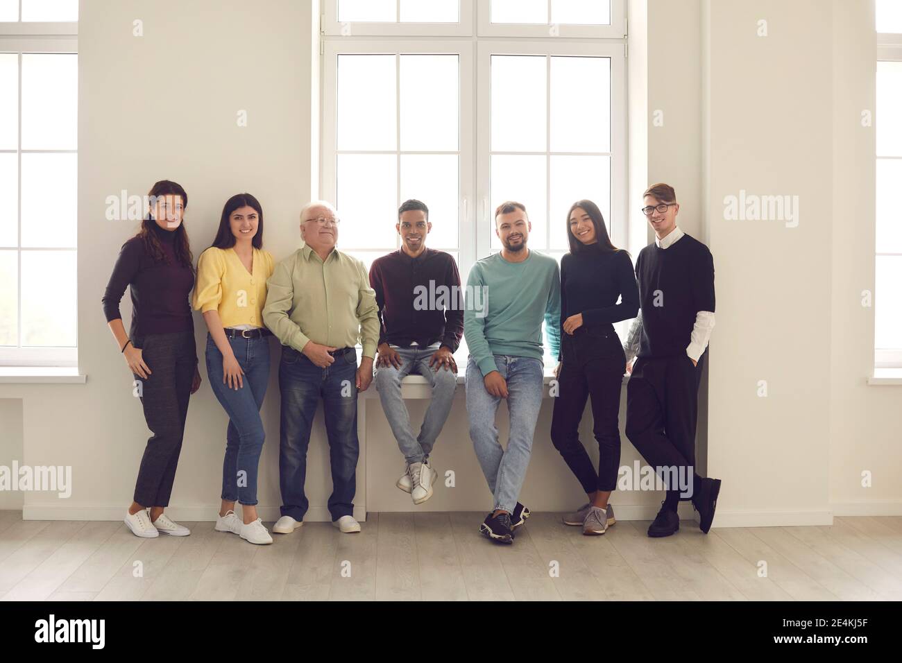 Team of cheerful diverse people standing by the window, smiling and ...