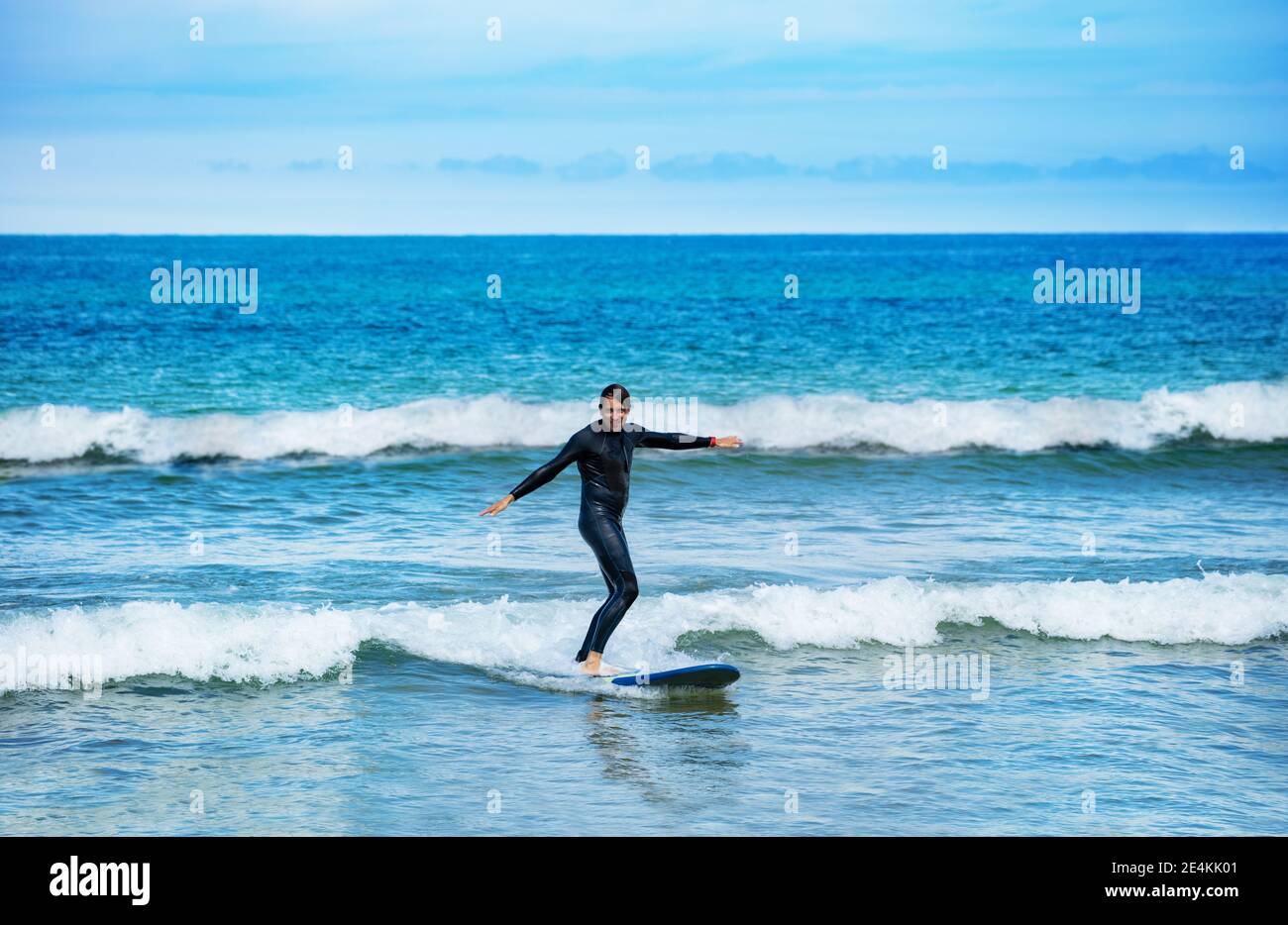 Portrait of the man riding the surfboard in the small waves learning to ...