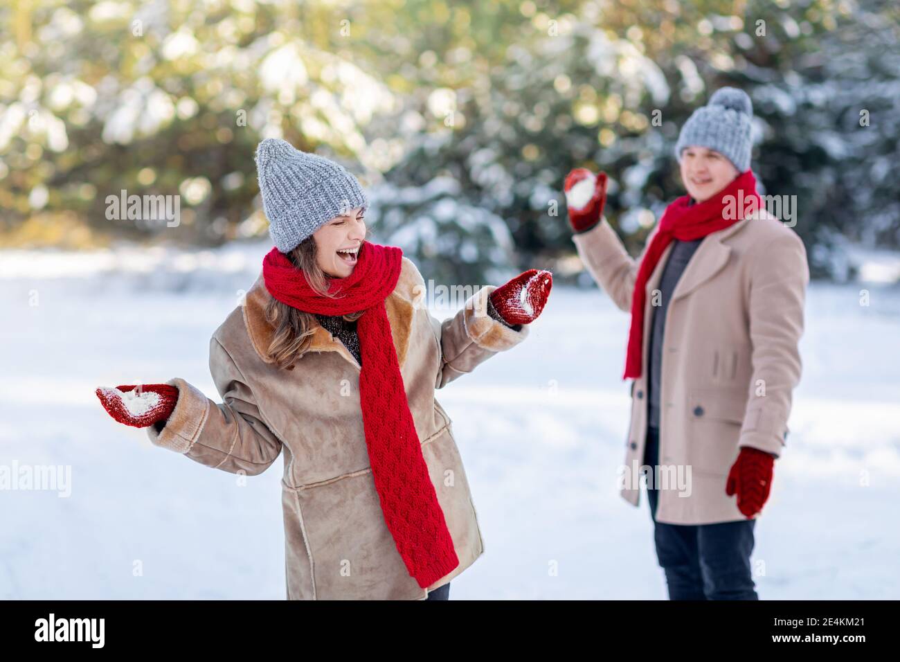 Cheerful young couple having snowball fight outdoors Stock Photo - Alamy